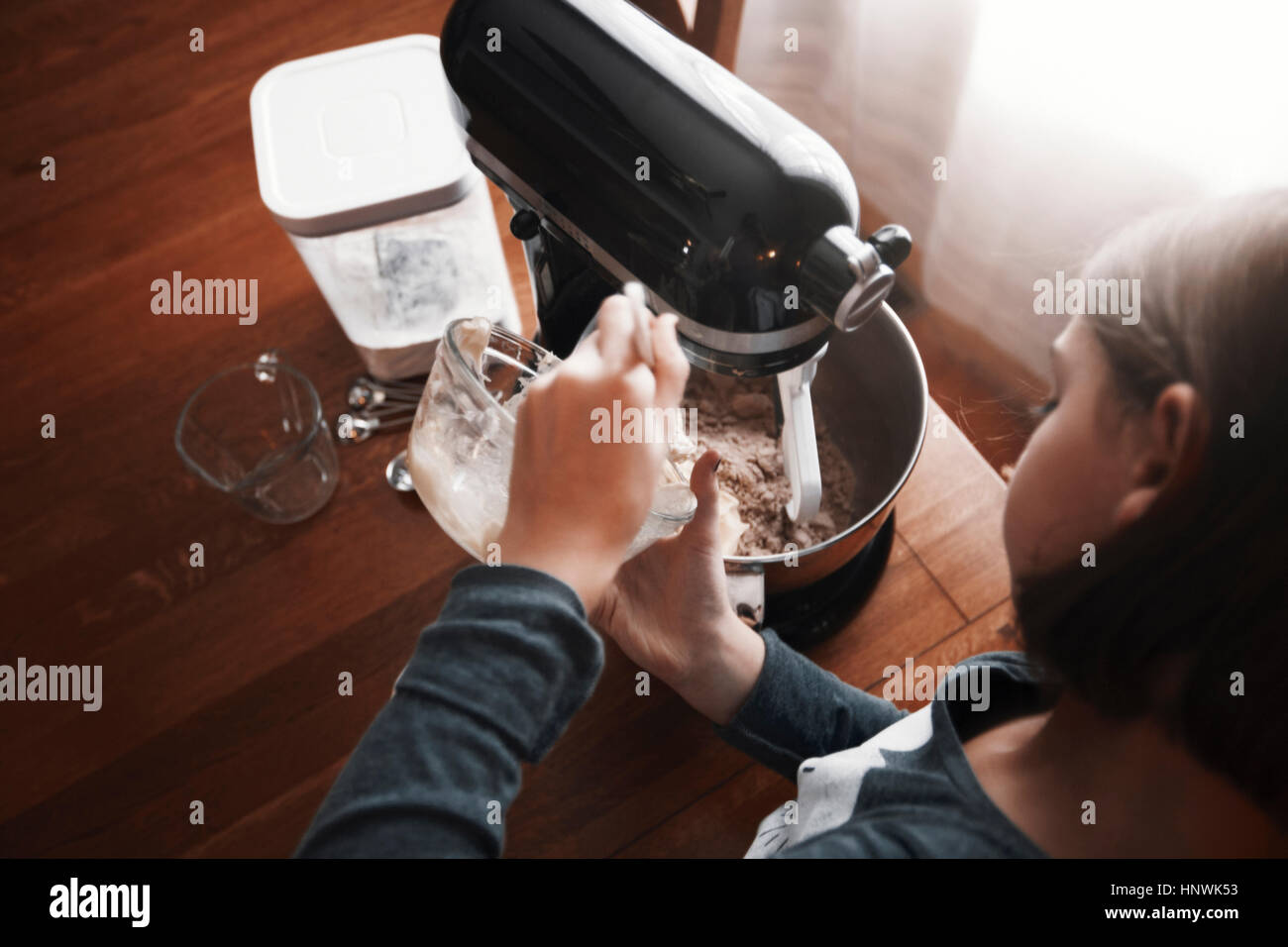 Young girl pouring ingredients into bowl of food mixer, overhead view ...