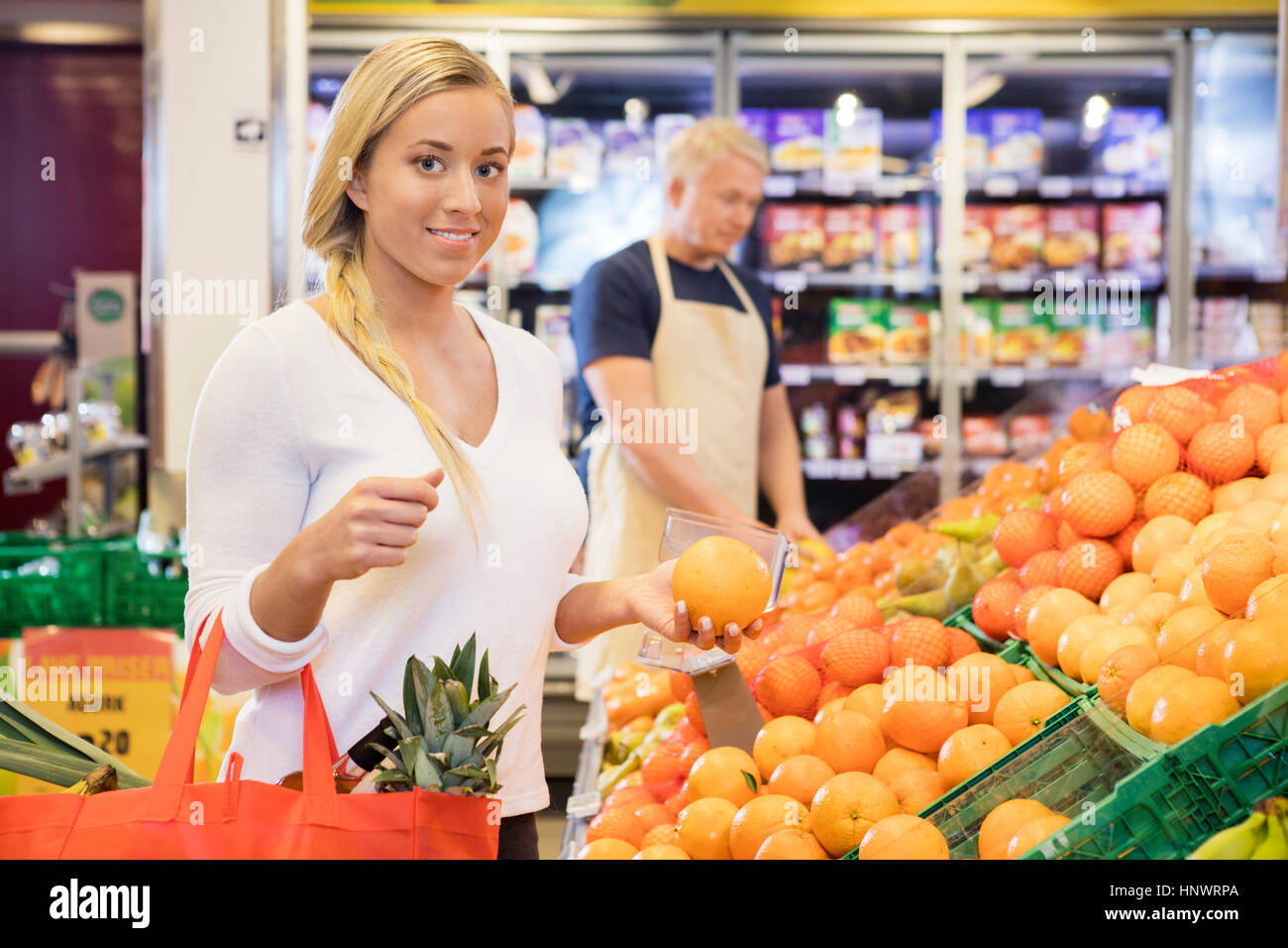 Female Customer Holding Orange In Grocery Store Stock Photo - Alamy