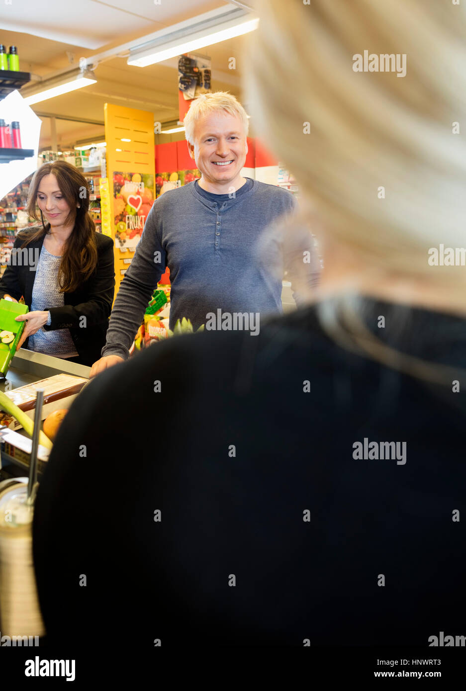 Customers Smiling At Checkout Counter Stock Photo - Alamy