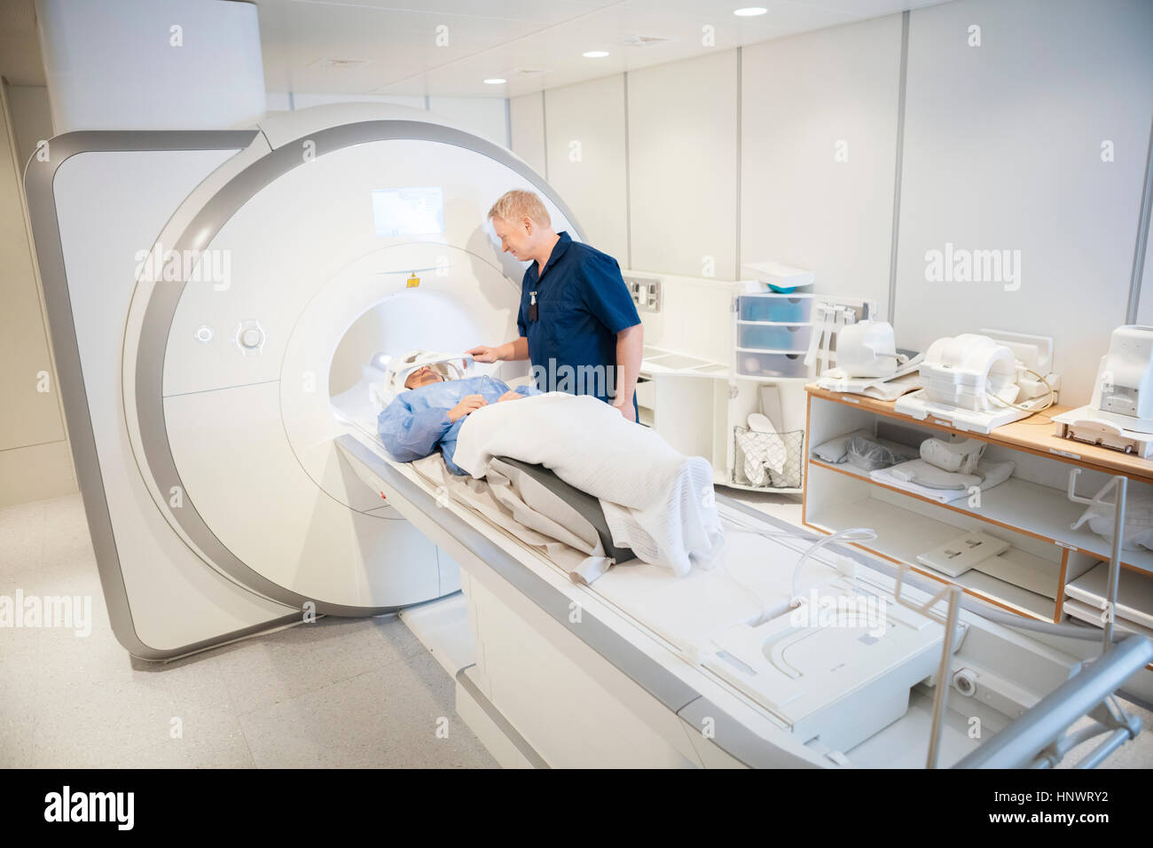 Radiologist Putting Coil On Female Patient's Head Undergoing MRI Stock ...