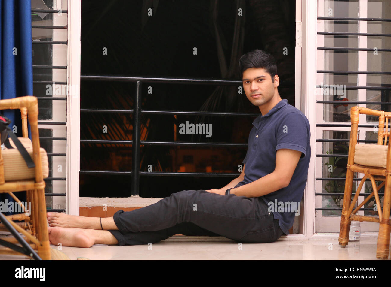 Young man sitting on ground looking at camera Stock Photo - Alamy