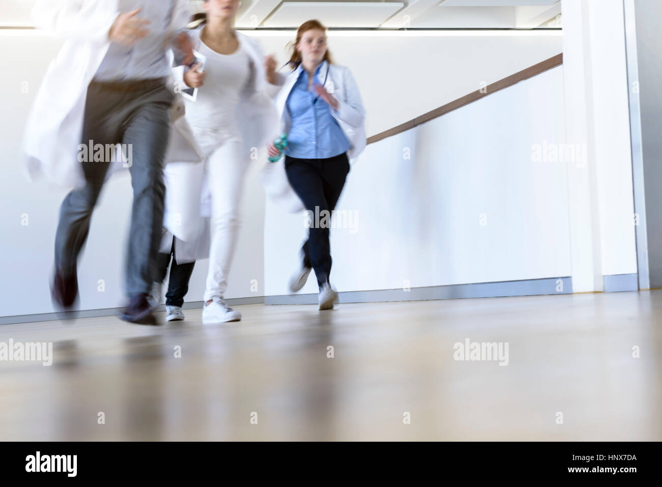 Male and female doctors running along hospital corridor Stock Photo - Alamy
