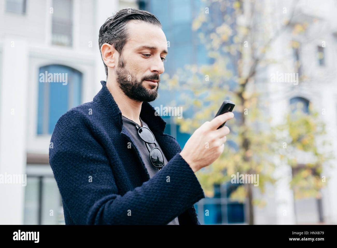 Man in street looking at mobile telephone Stock Photo - Alamy