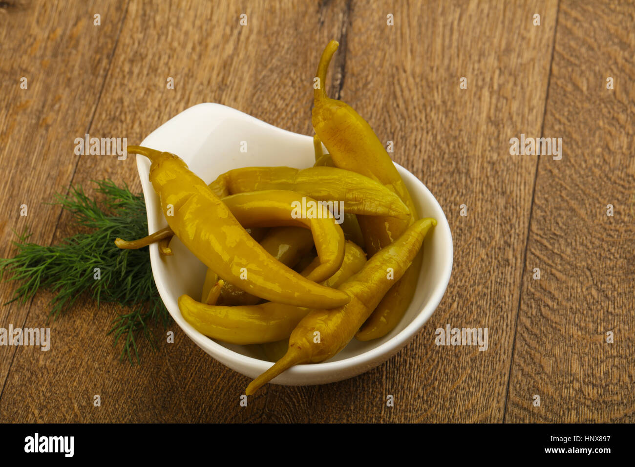 Pickled green pepperoni pepper in the bowl on wood background Stock ...