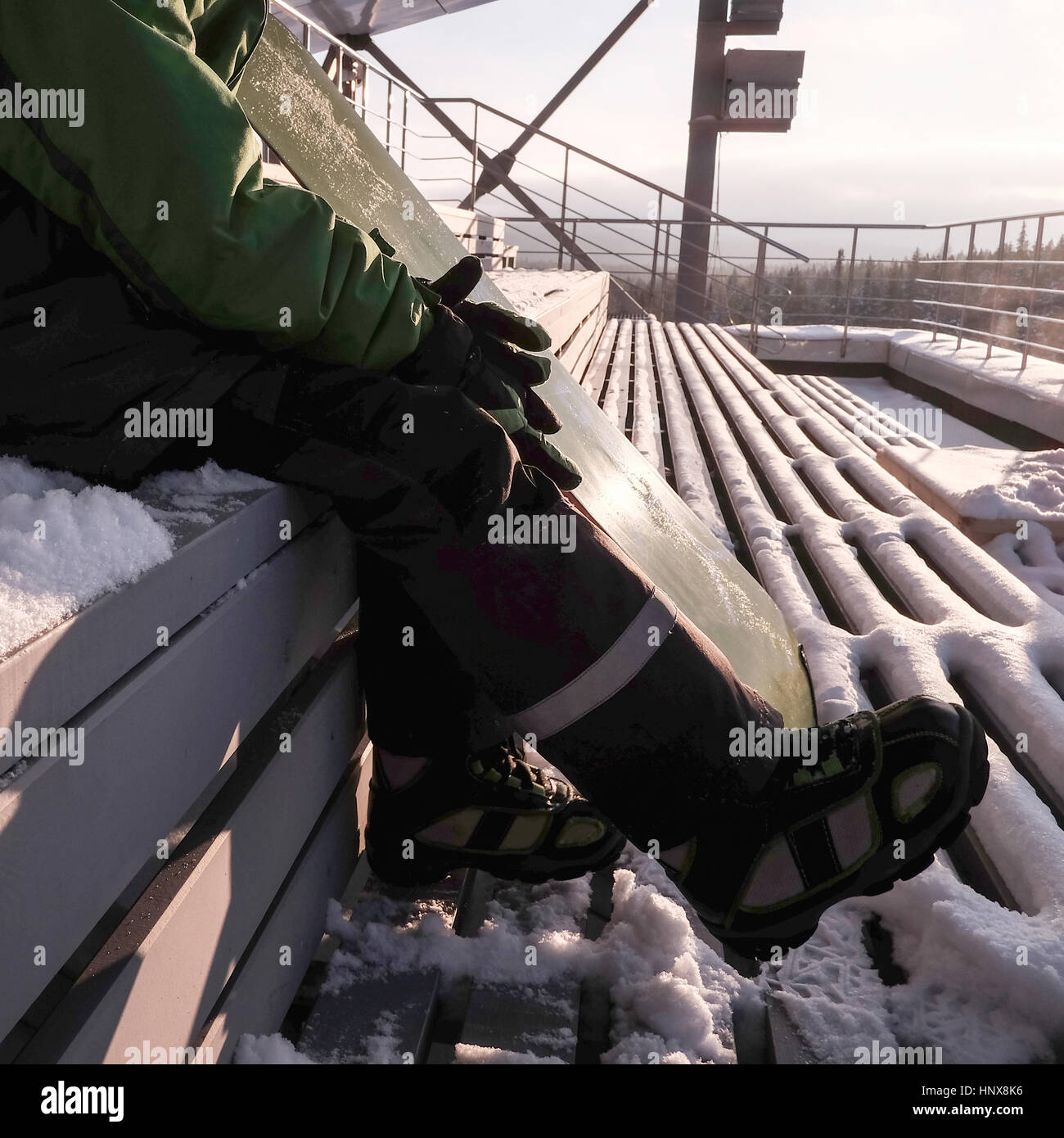 Cropped view of boy wearing ski suit sitting on bench Stock Photo - Alamy