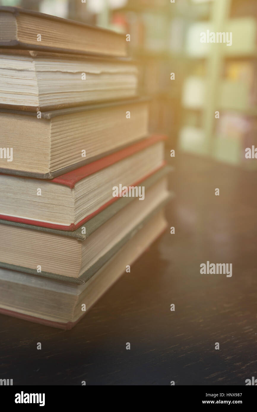 old book stack on wooden table with blur library background Stock Photo ...