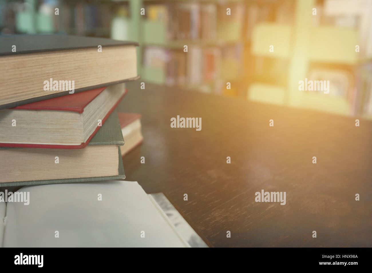 old book stack on wooden table with blur library background Stock Photo ...