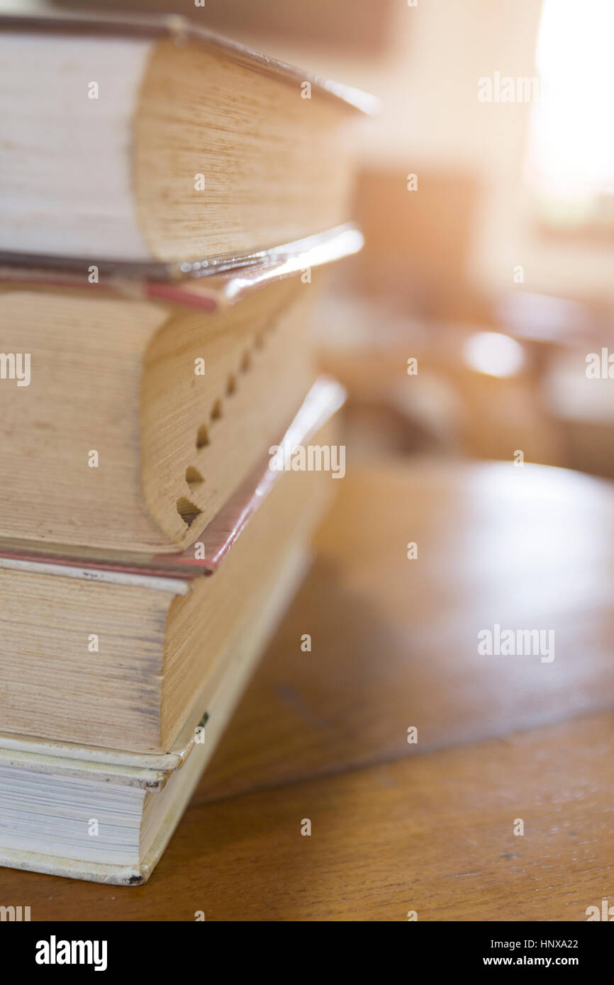 old book stack on wooden table with blur library background Stock Photo - Alamy