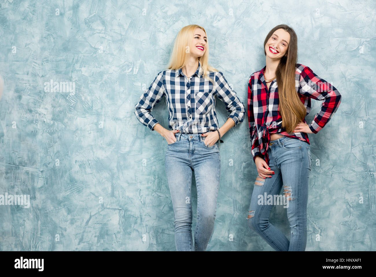 Portrait of two female friends in checkered shirts and jeans together ...