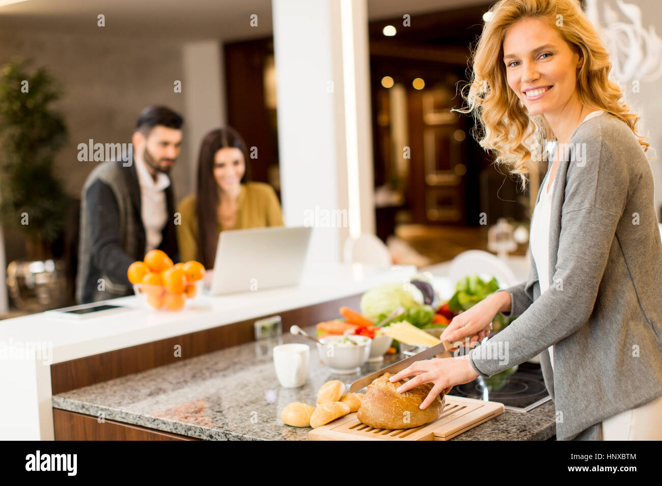 Happy group of young men and women cooking together at home in modern ...