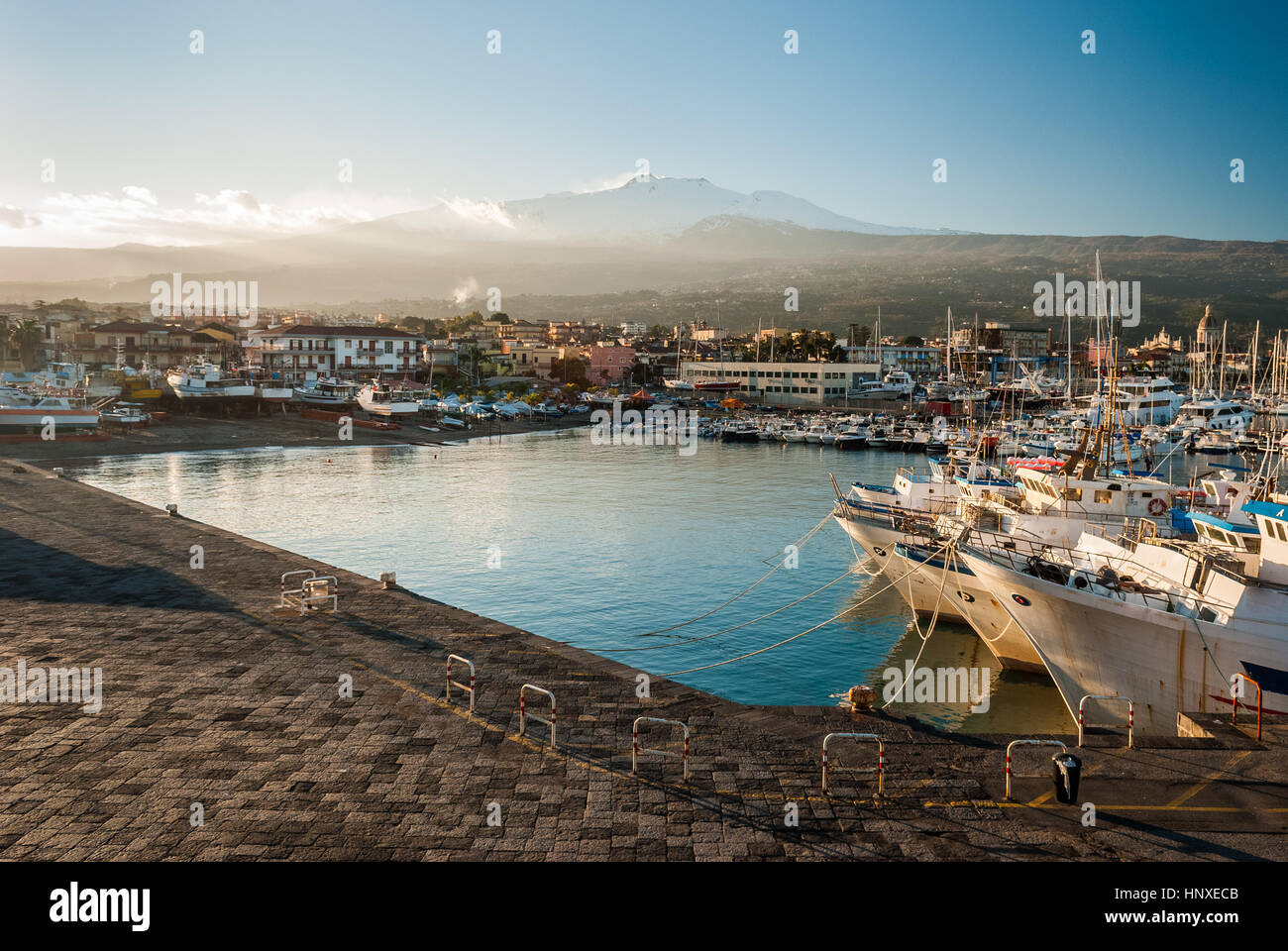 The harbor of Riposto during the sunset; snowy volcano Etna in the ...