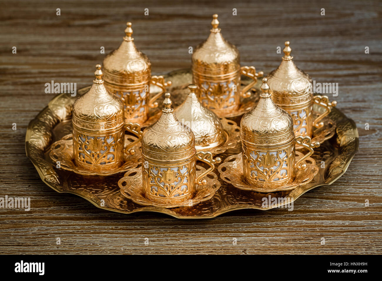 Traditional golden coffee cup set in a tray on brown wooden background ...