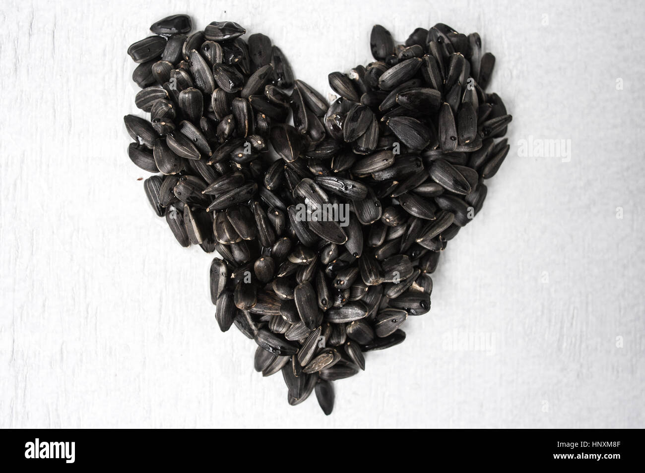 Black sunflower bird seed forms a heart shape on white background Stock ...