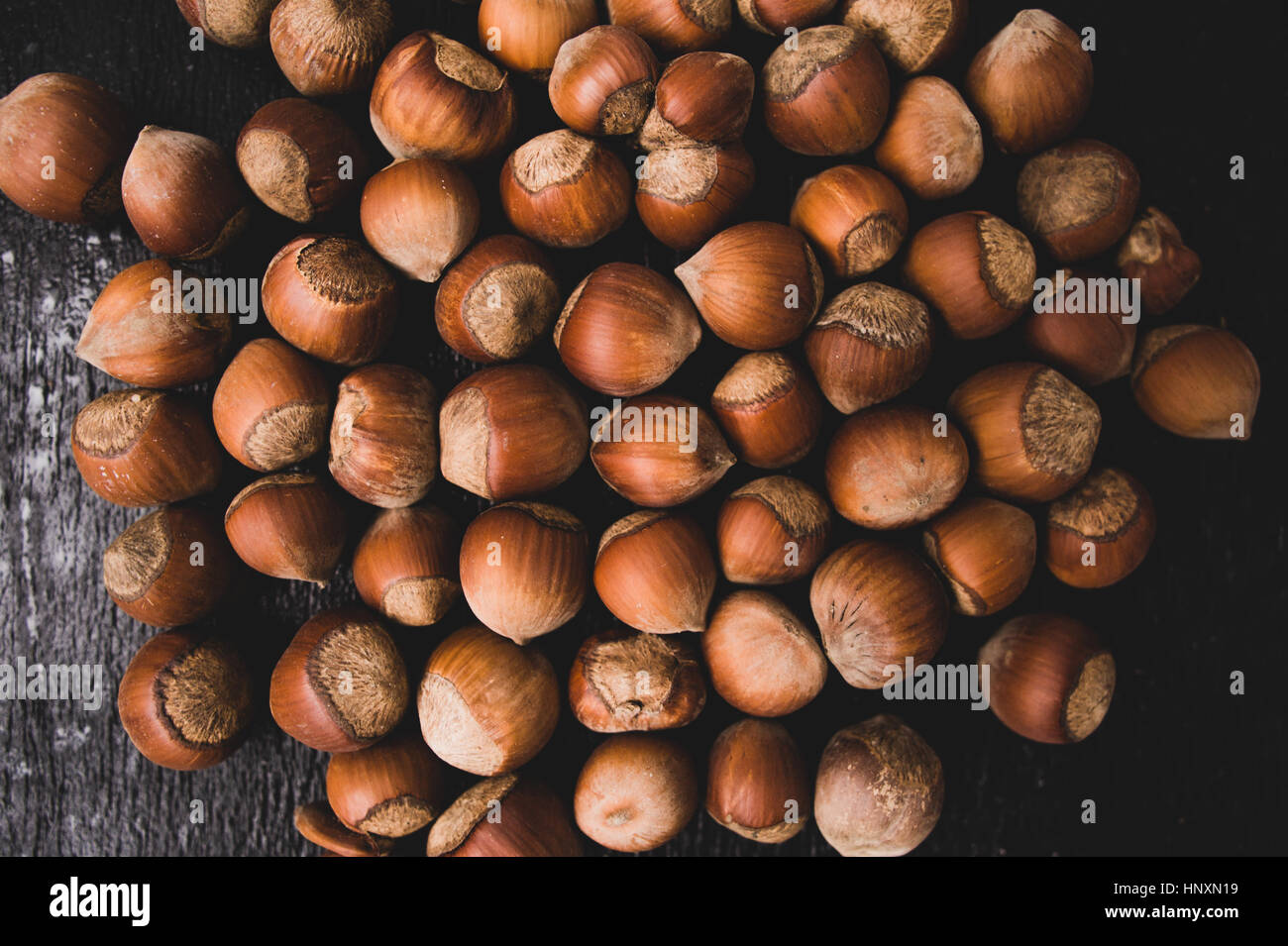 Heap of hazelnuts on a dark wood background Stock Photo - Alamy