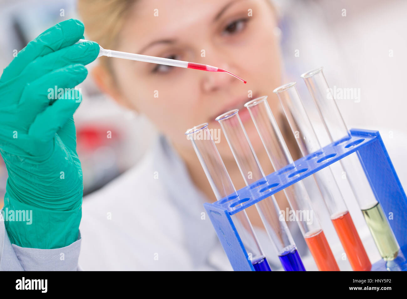 A young chemist holding test tube with liquid during chemical ...