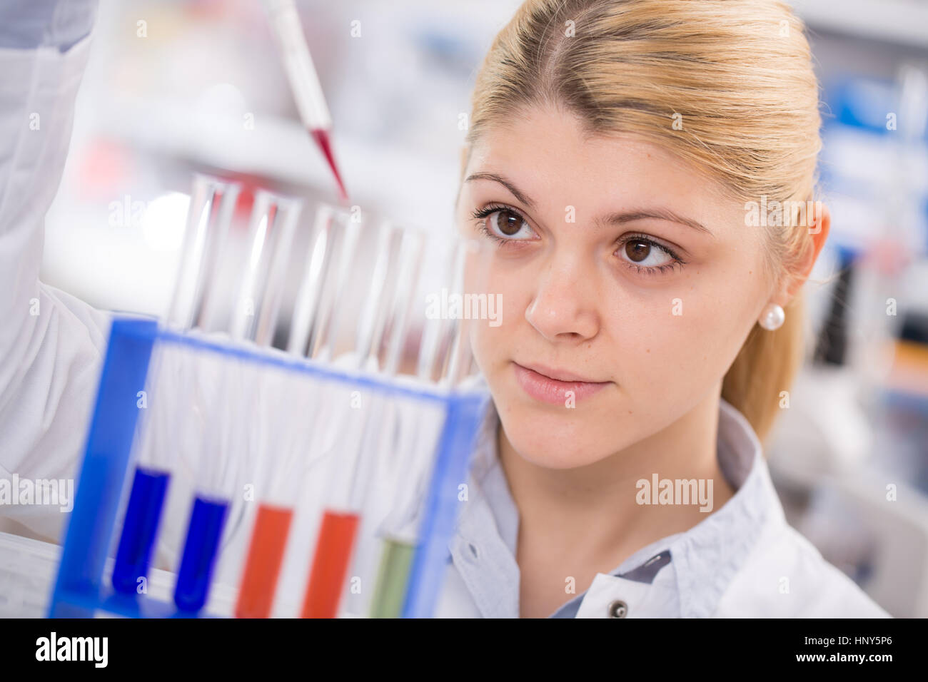 A young chemist holding test tube with liquid during chemical ...