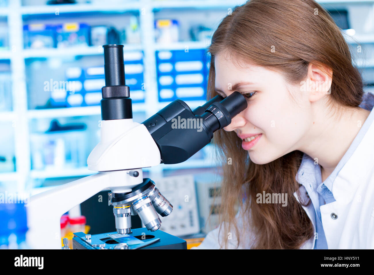 Young scientist studying new substance or virus in microscope ...