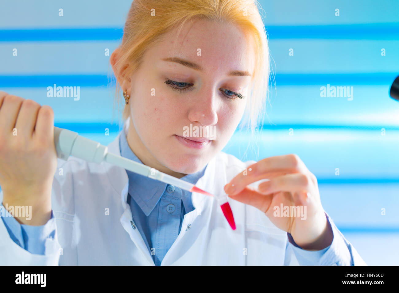 A young chemist holding test tube with liquid during chemical ...