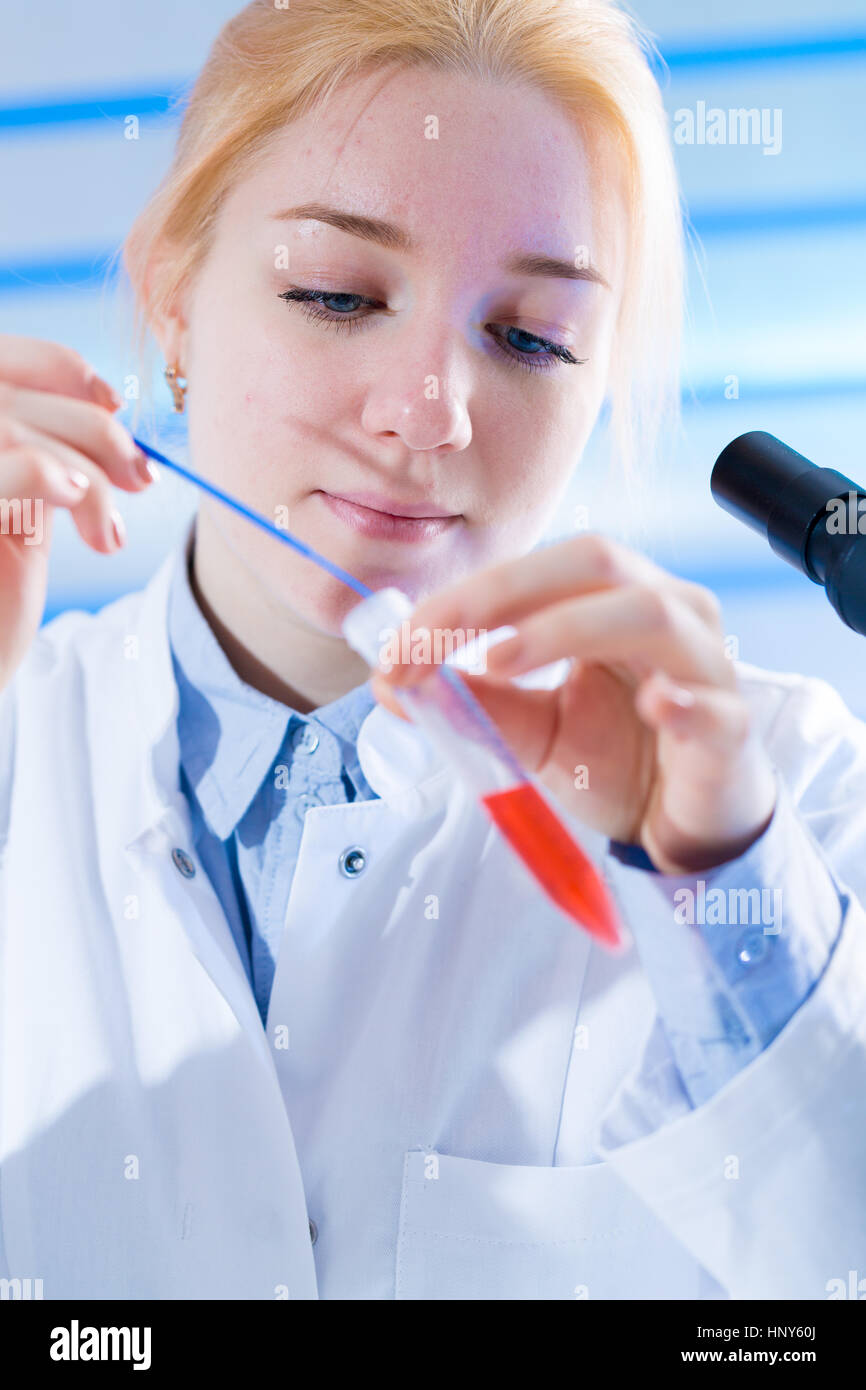 Young women use laboratory dispenser or pipette in microbiological or ...
