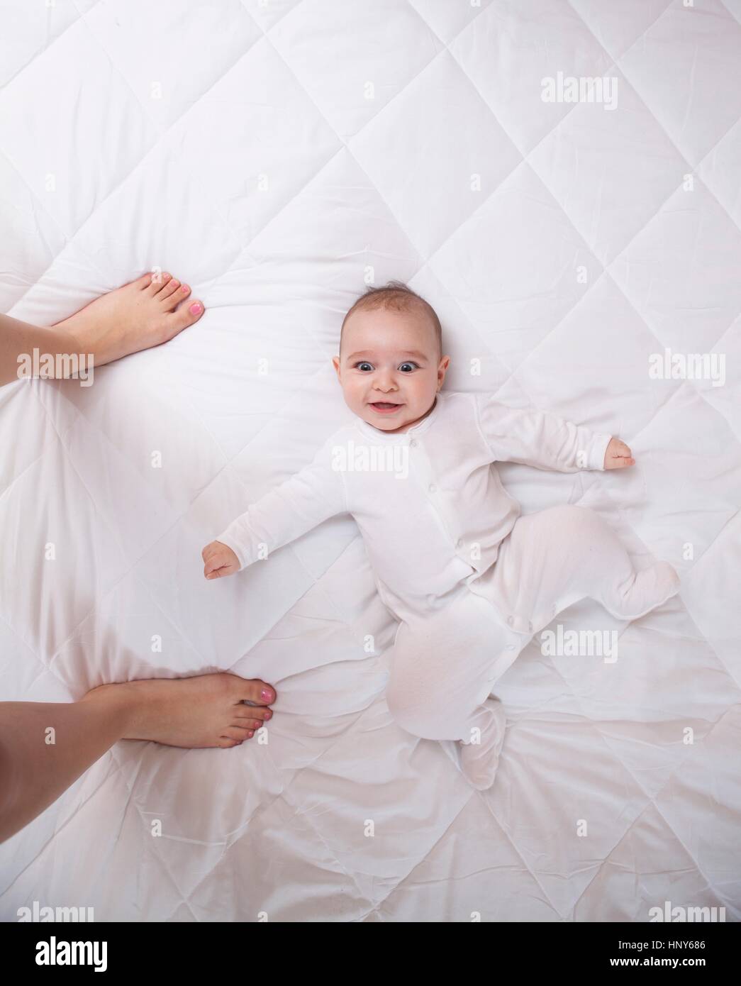 Happy addorable baby boy and the legs of his mother who taking a ...