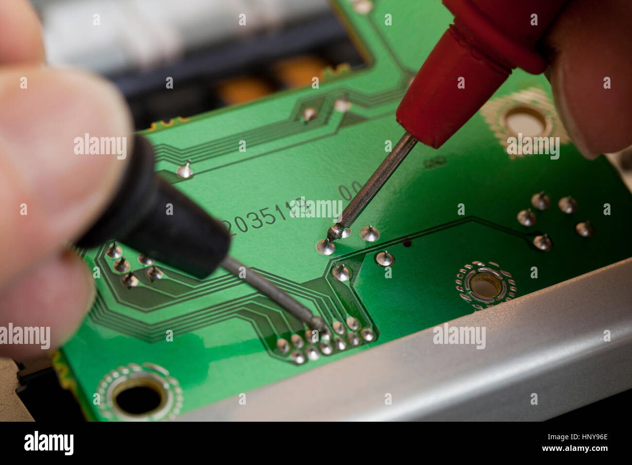 Technician testing contact points on circuit board with a voltmeter ...