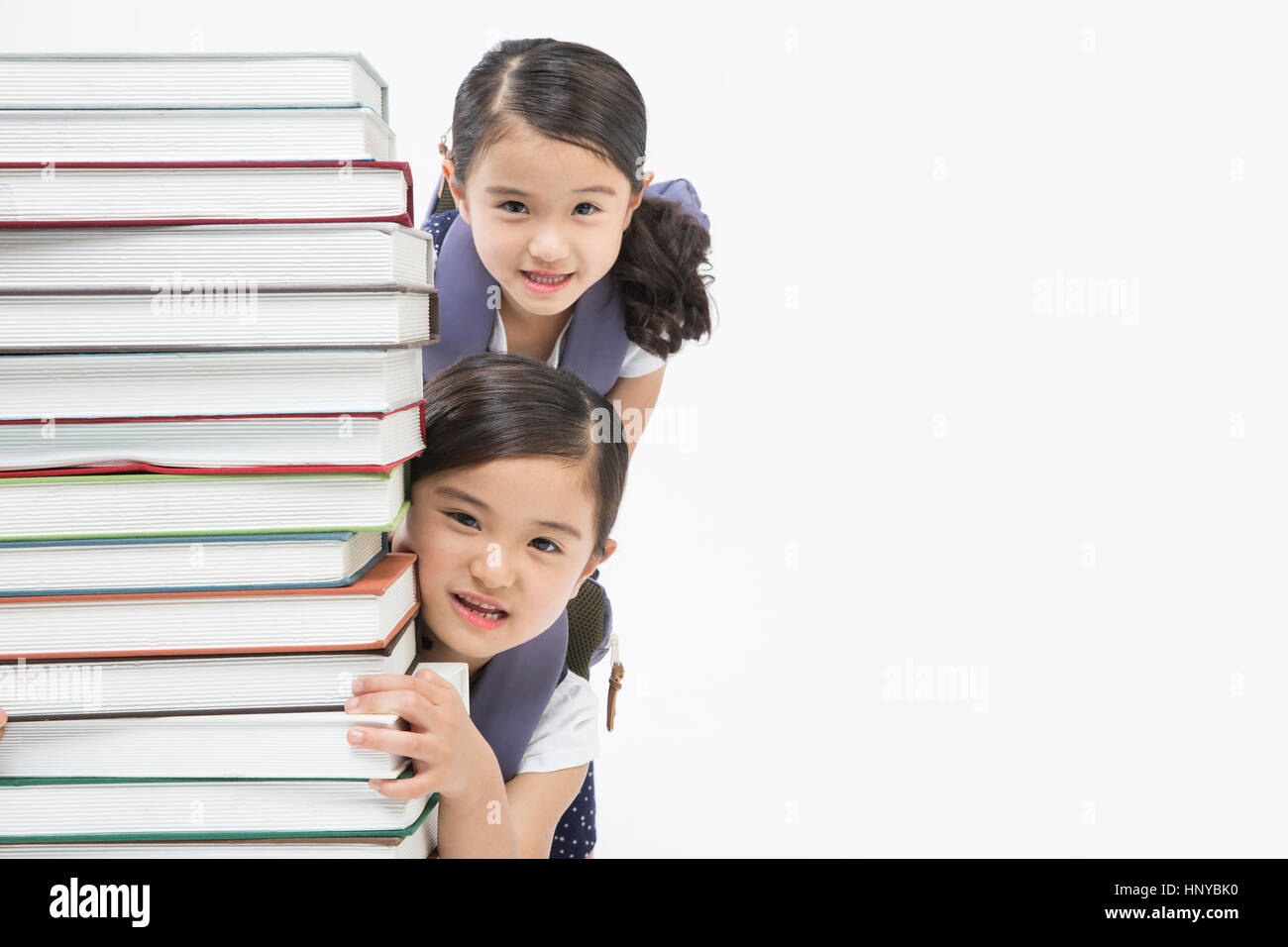 Portrait of smiling twin girls with stacked books Stock Photo - Alamy