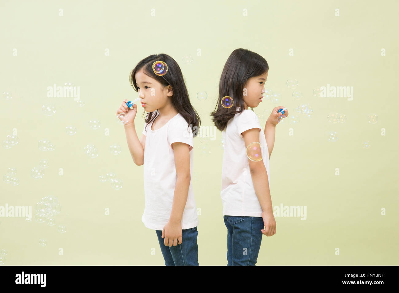 Twin girls standing back to back Stock Photo - Alamy