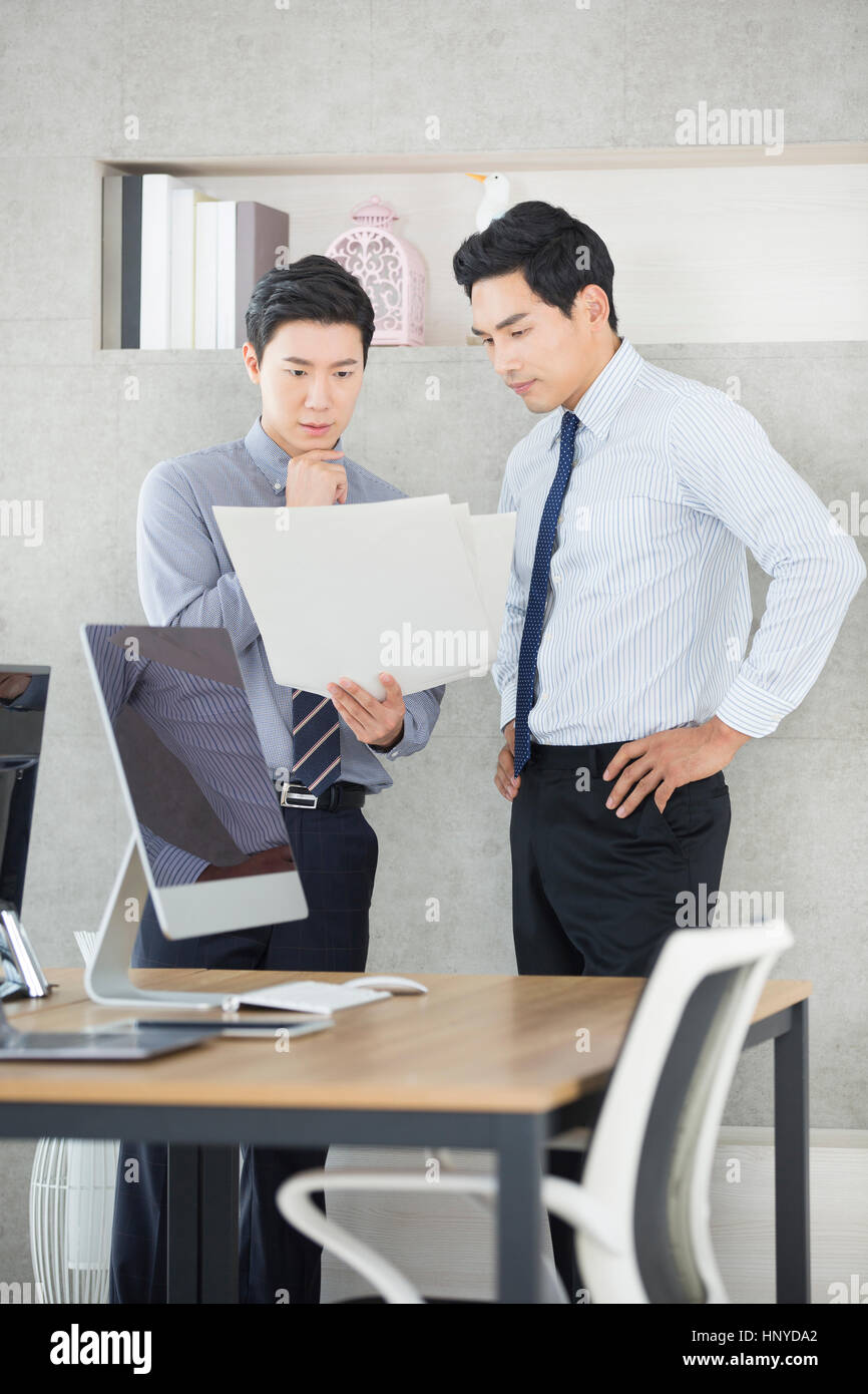 Two businessmen sharing papers at office Stock Photo - Alamy