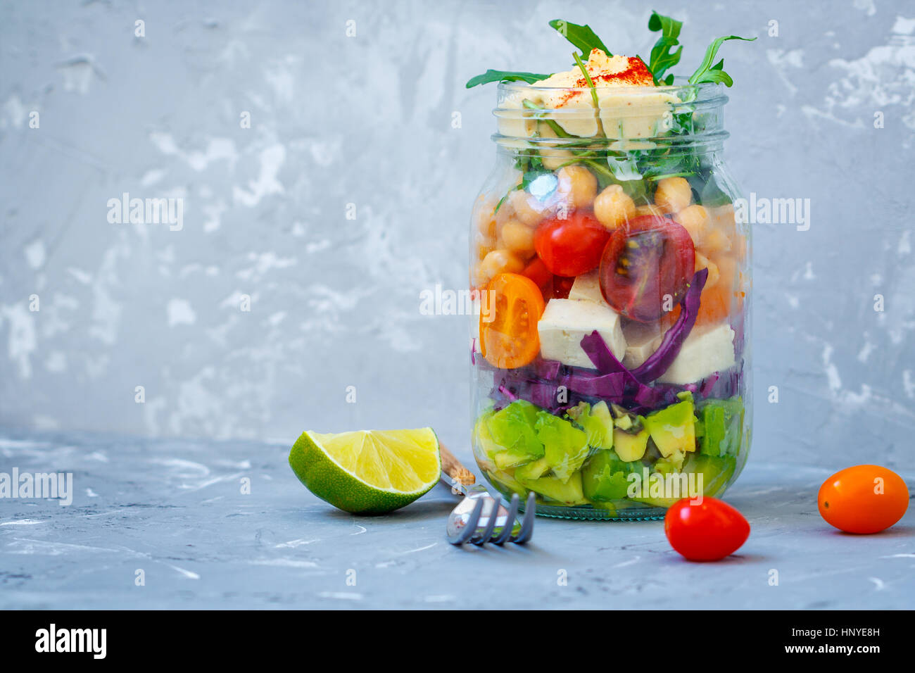 Healthy take-away lunch jar with guacamole, tofu, vegetables, chickpeas ...