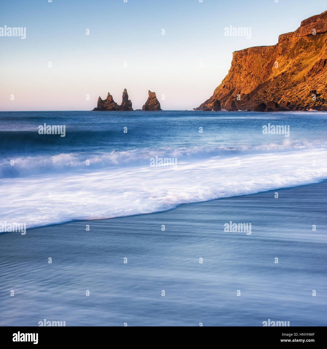 Vik beach at sunrise with waves in foreground and Reynisdranger basalt ...