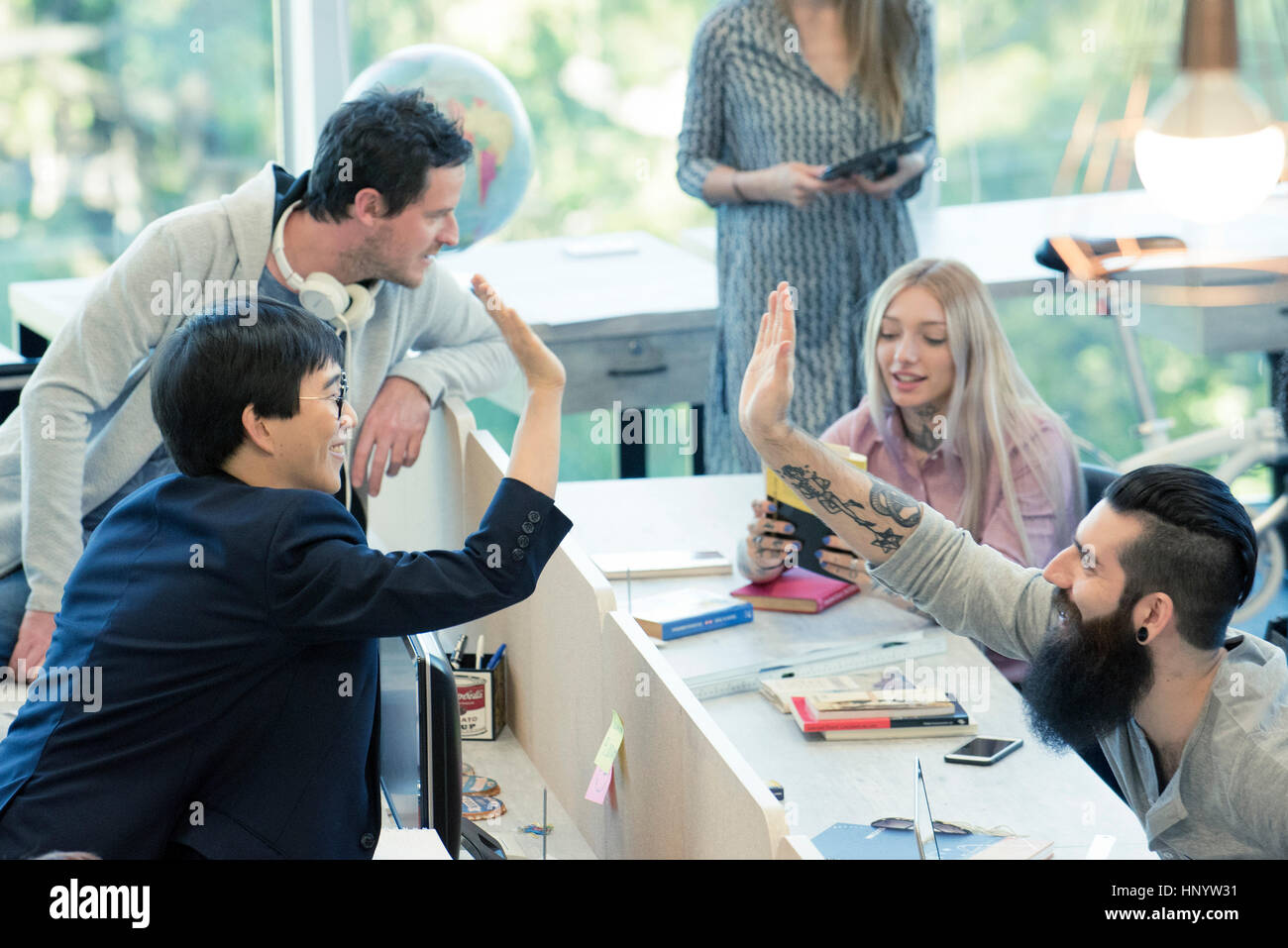 Colleagues high-fiving in casual office Stock Photo - Alamy