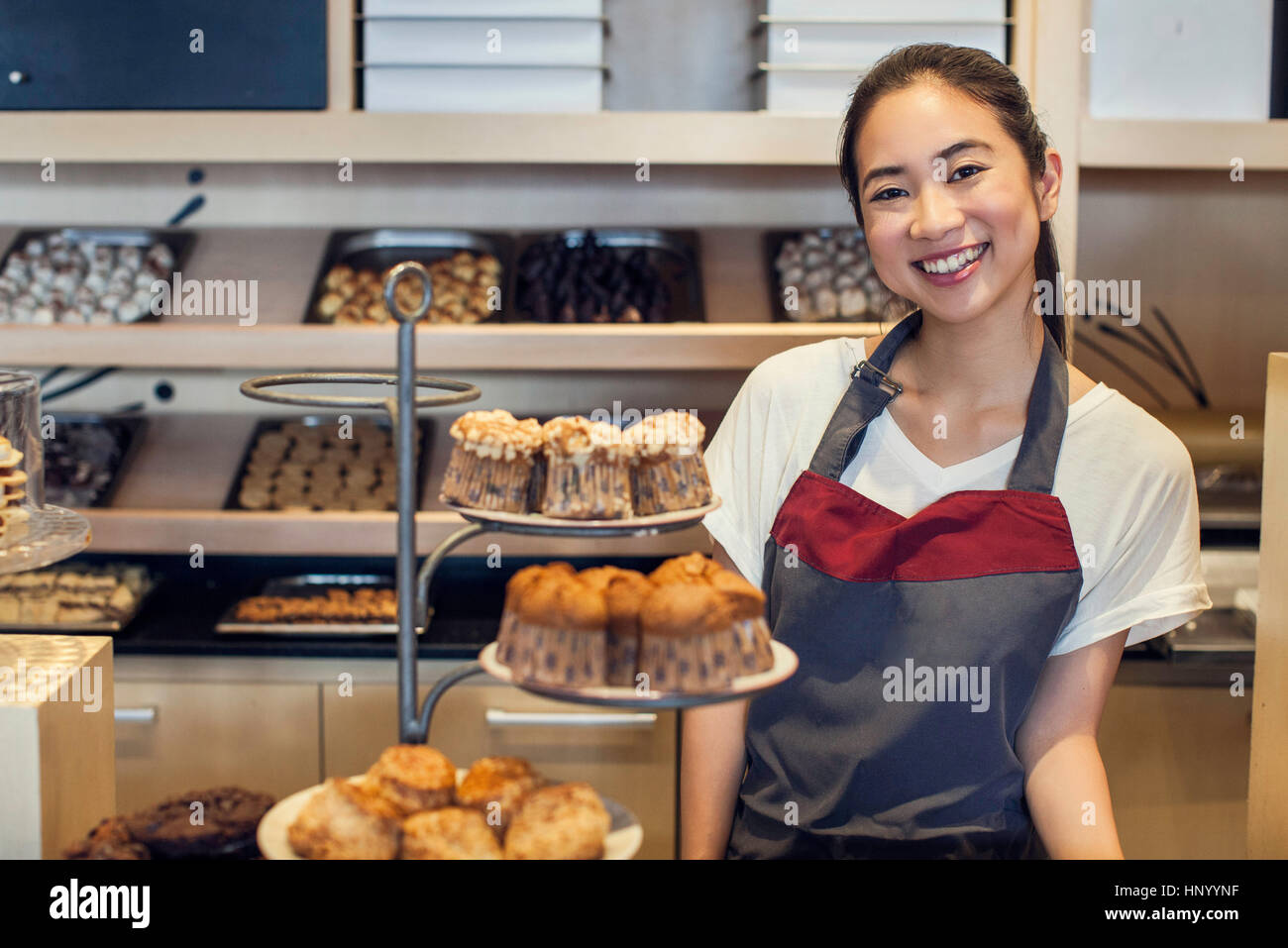 Woman smiling behind bakery counter, portrait Stock Photo - Alamy