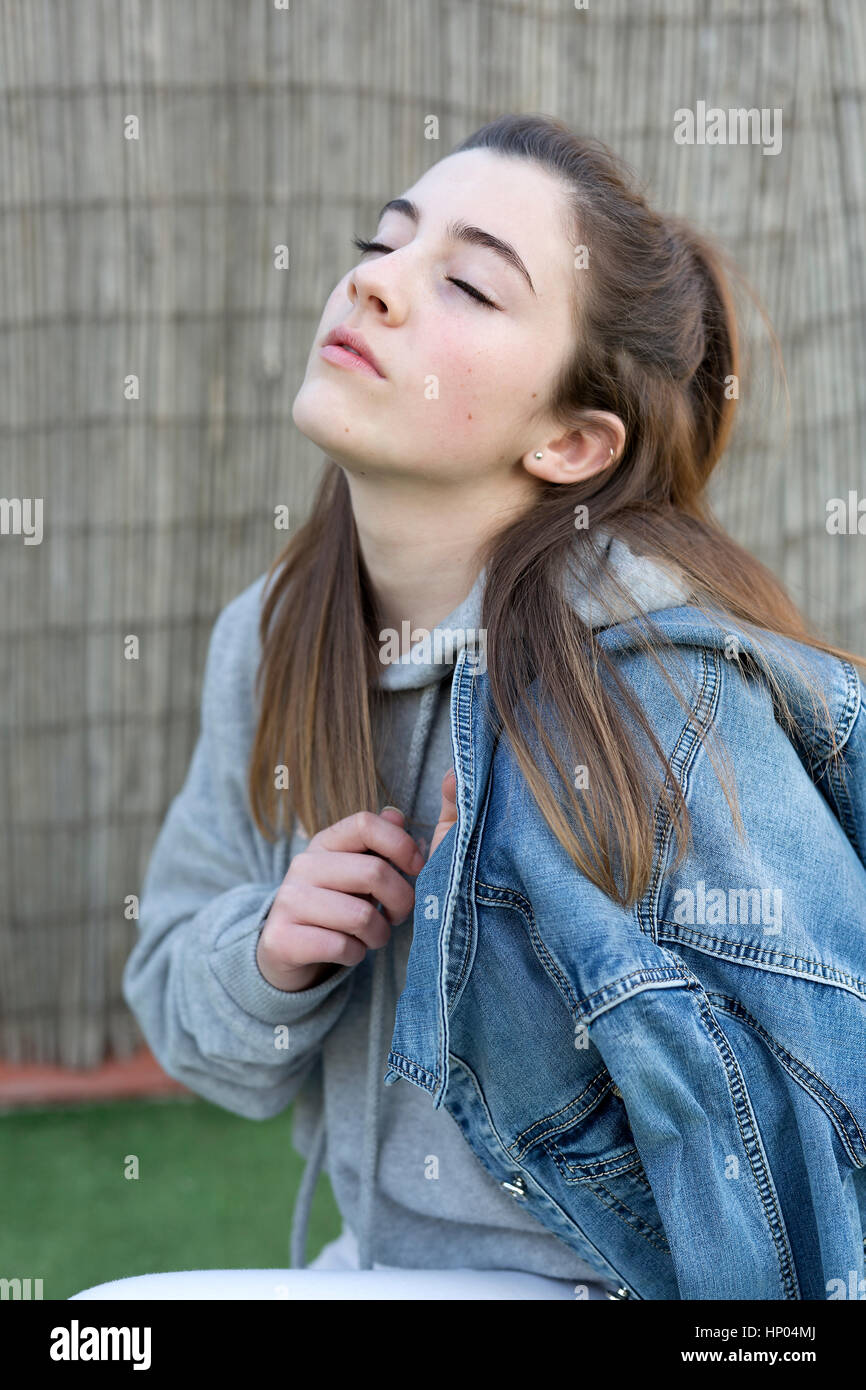 Young woman with a denim jacket over her shoulder and eyes closed ...