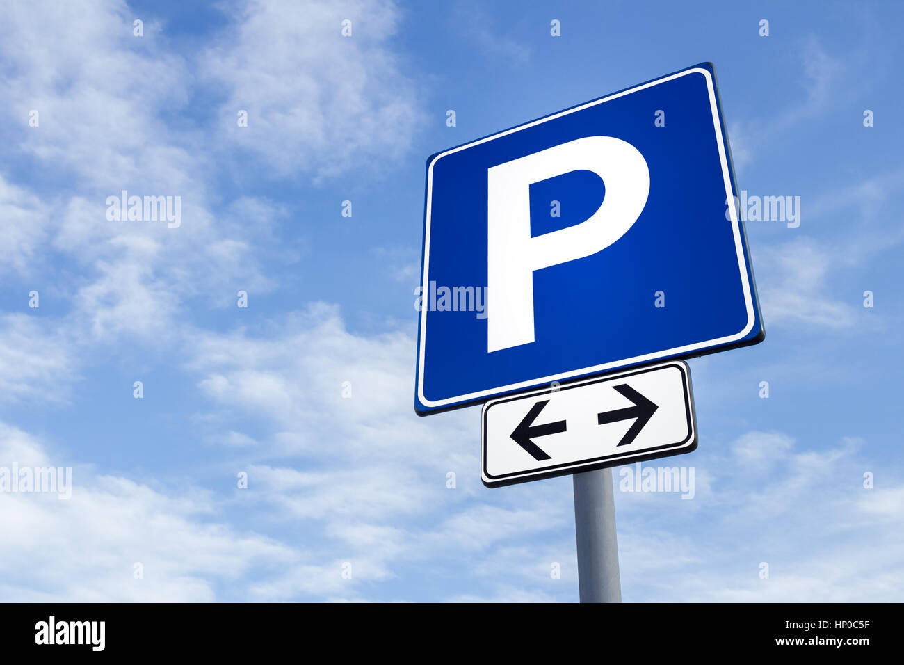 Car parking directional sign against a partly cloudy sky background ...