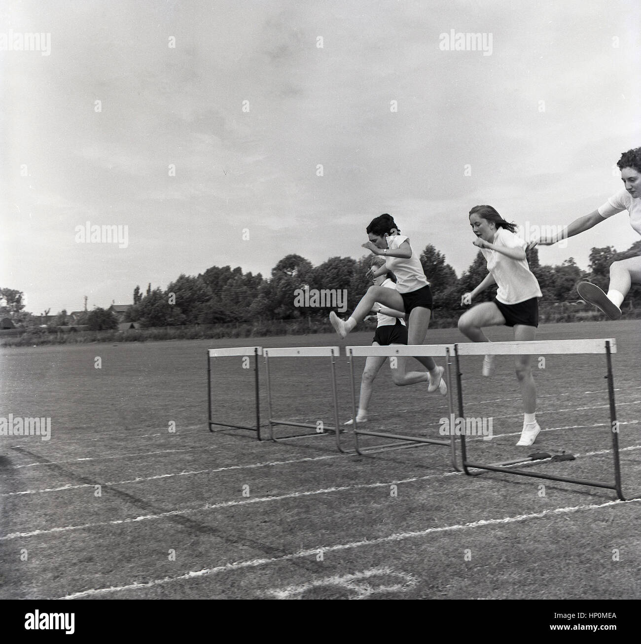 1960s, historical, young school girls taking part in a hurdles race on ...