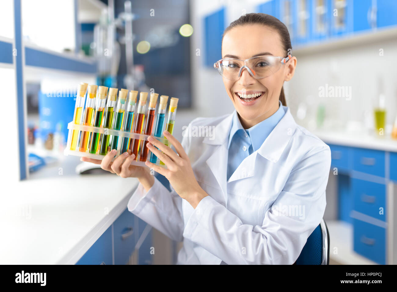 smiling scientist showing laboratory tubes and looking to camera Stock ...
