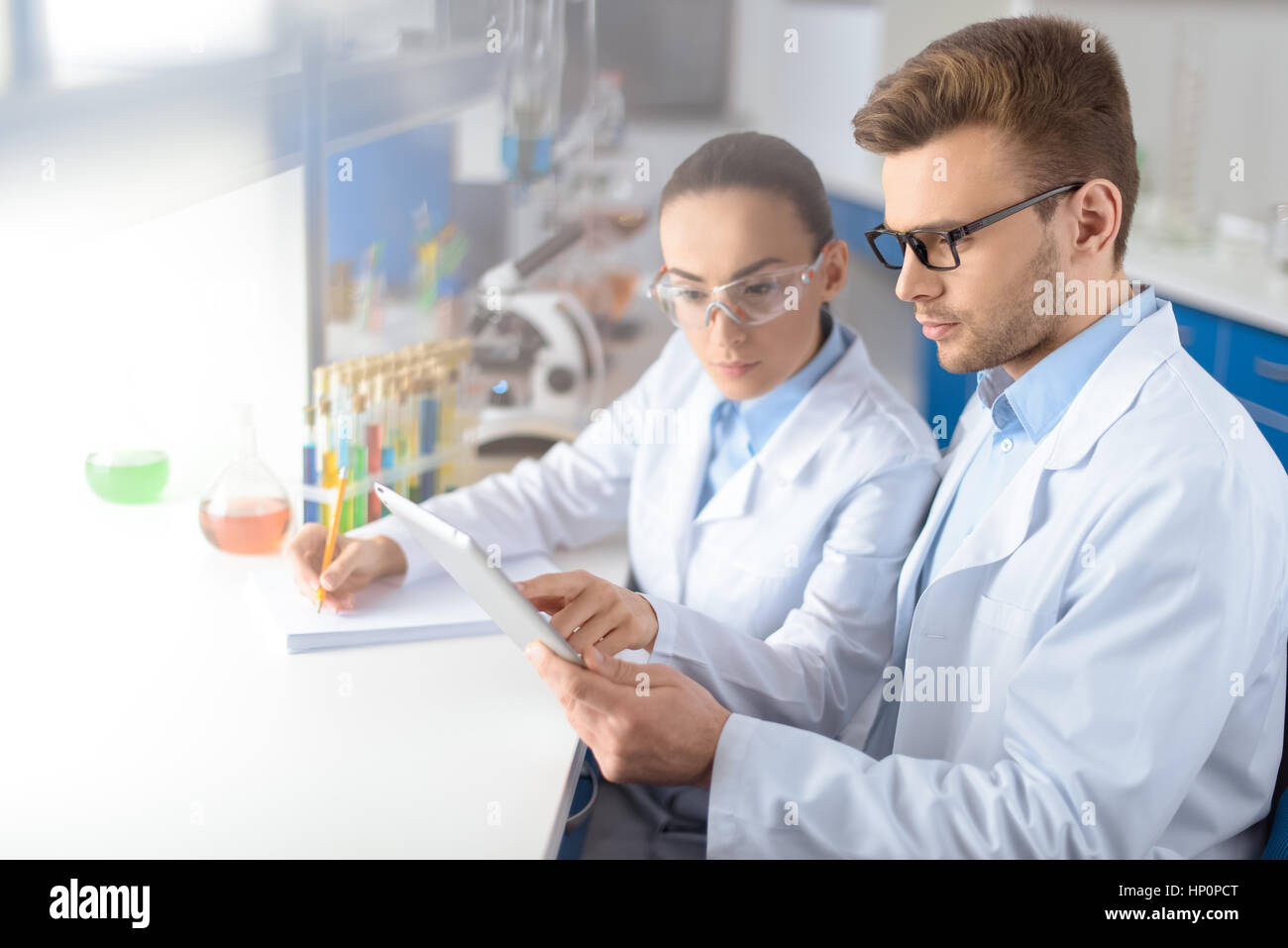 concentrated scientists using digital tablet during work in laboratory ...