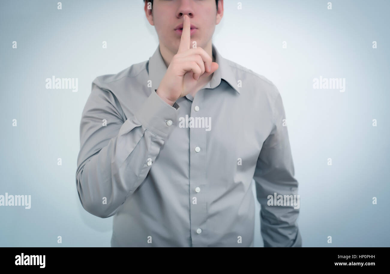 Young man is gesturing hush with his finger on his lips Stock Photo - Alamy