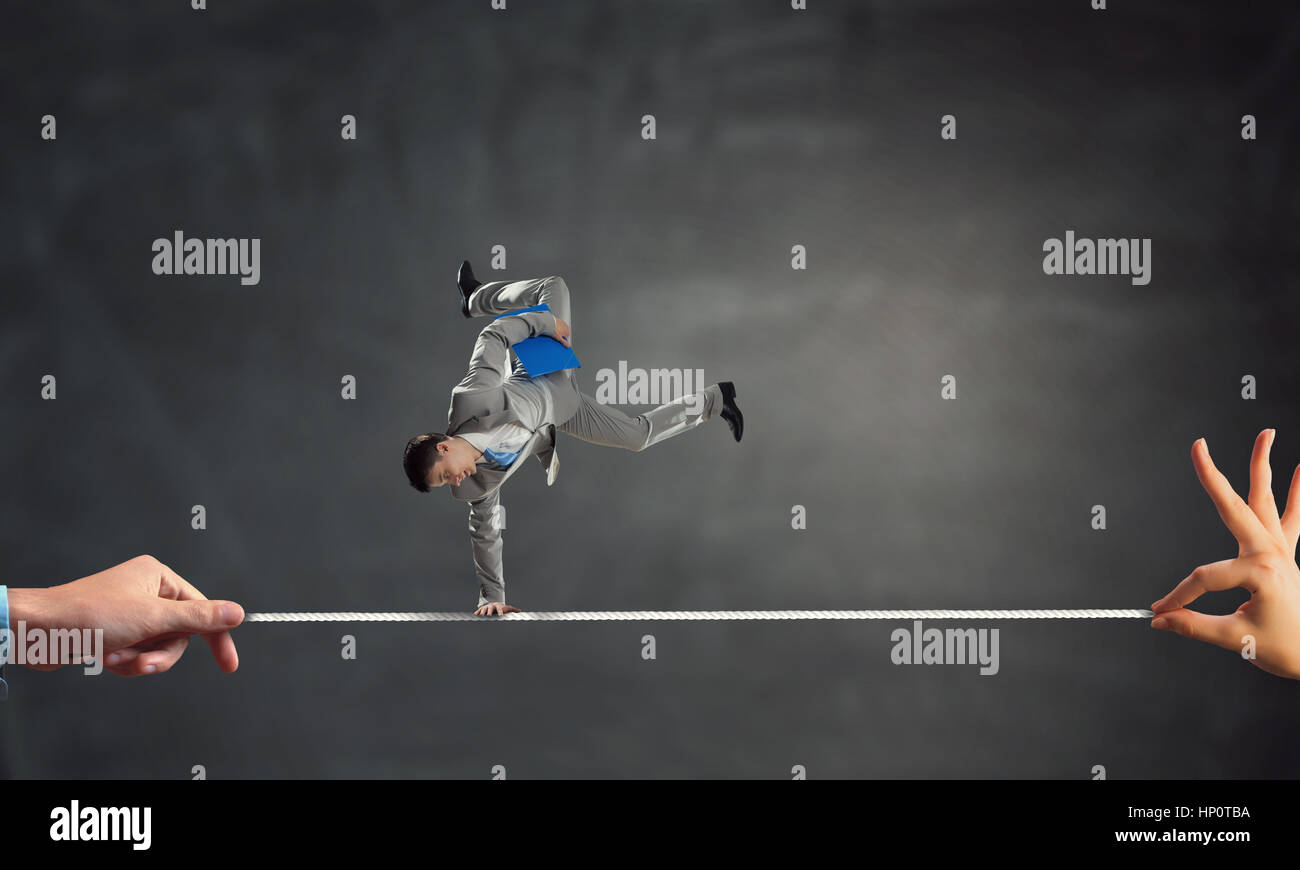 Young cheerful businessman doing handstand on strained rope Stock Photo ...