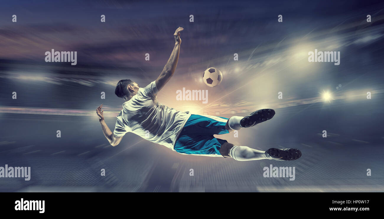 Football player at stadium hitting ball. Mixed media Stock Photo - Alamy