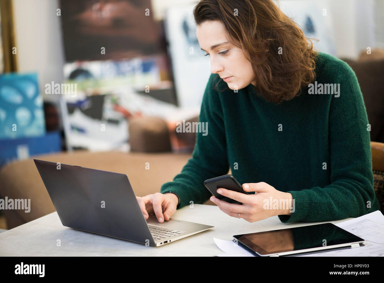 Woman multi-tasking with the help of laptop computer, digital tablet ...