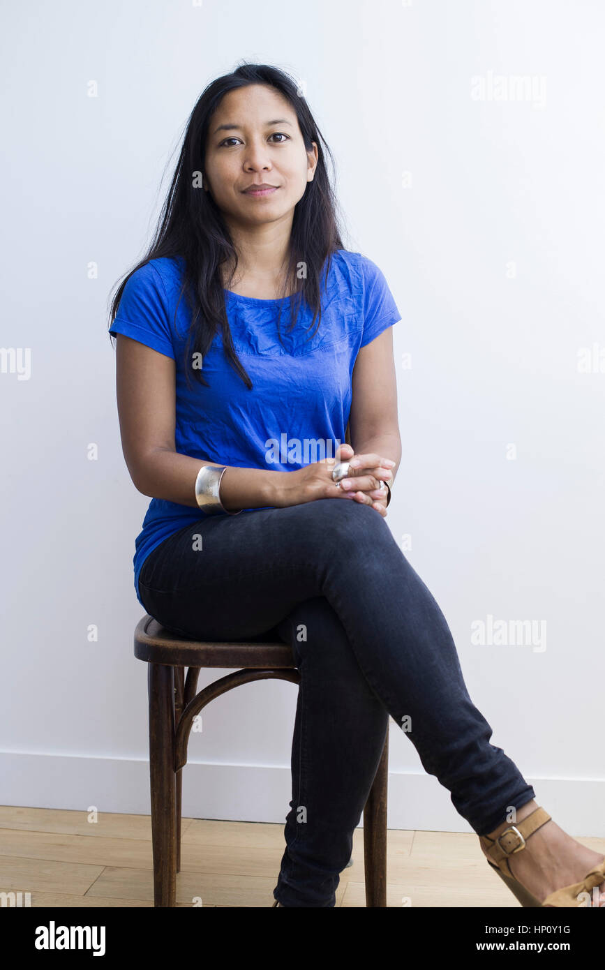 Woman sitting in chair with legs crossed, portrait Stock Photo - Alamy