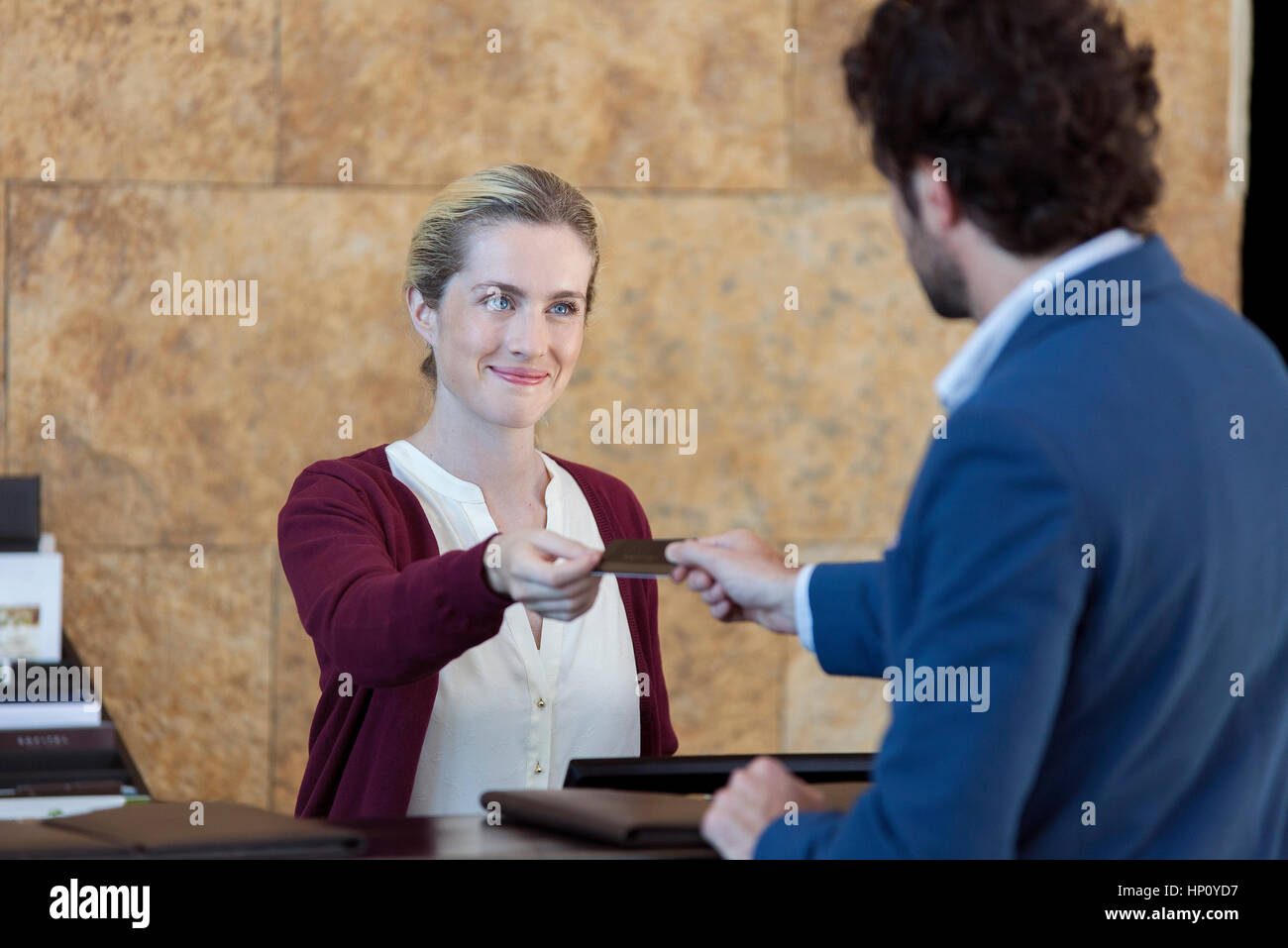 Friendly hotel receptionist taking customer's credit card Stock Photo ...
