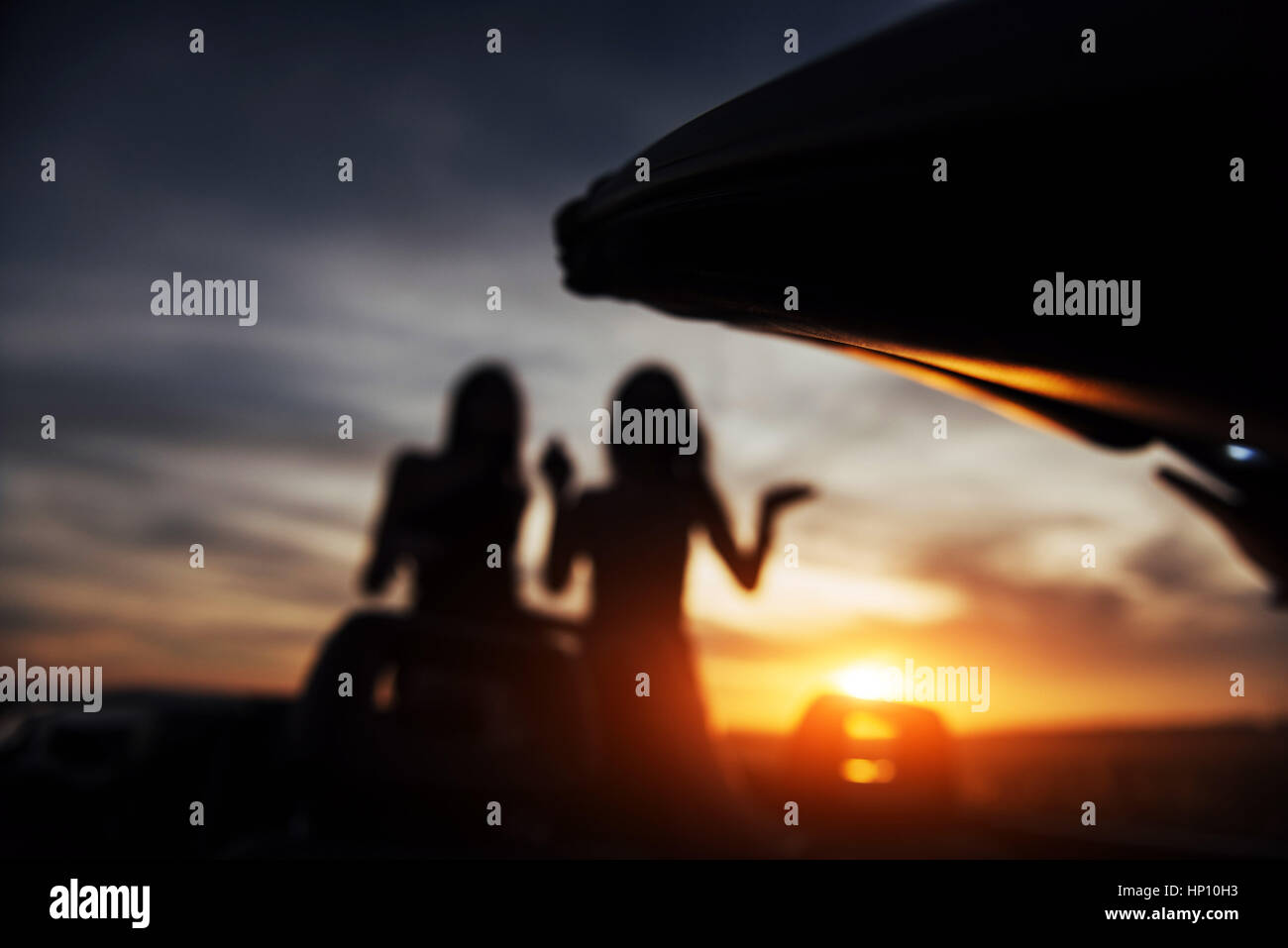 Two girls happy to pose next a black car Stock Photo - Alamy
