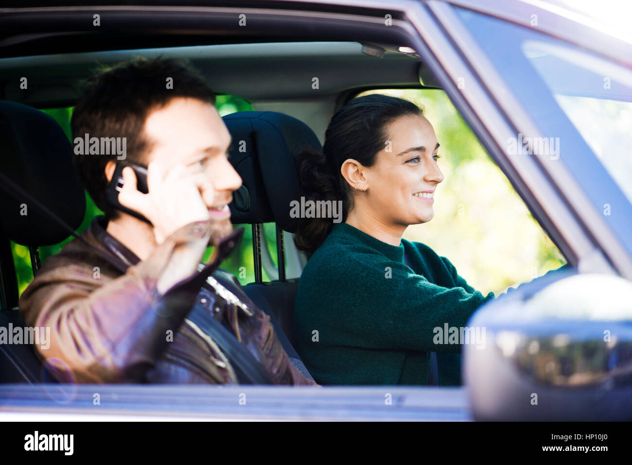 Woman driving while passenger chats on phone Stock Photo - Alamy