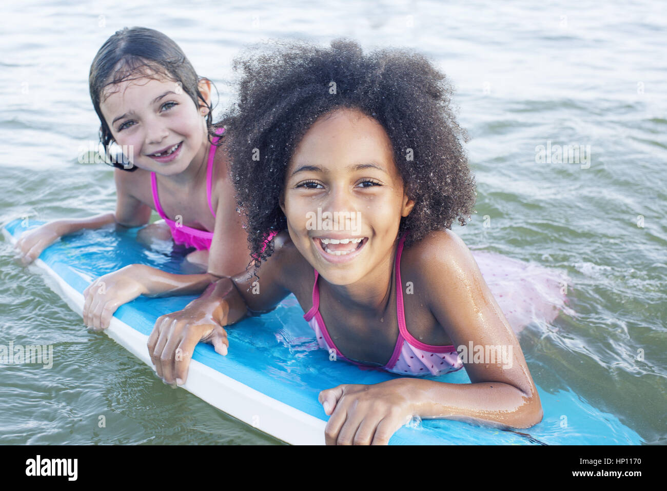 Girls floating on body board in water Stock Photo - Alamy