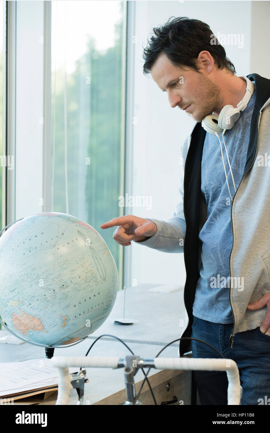Man looking at globe Stock Photo - Alamy