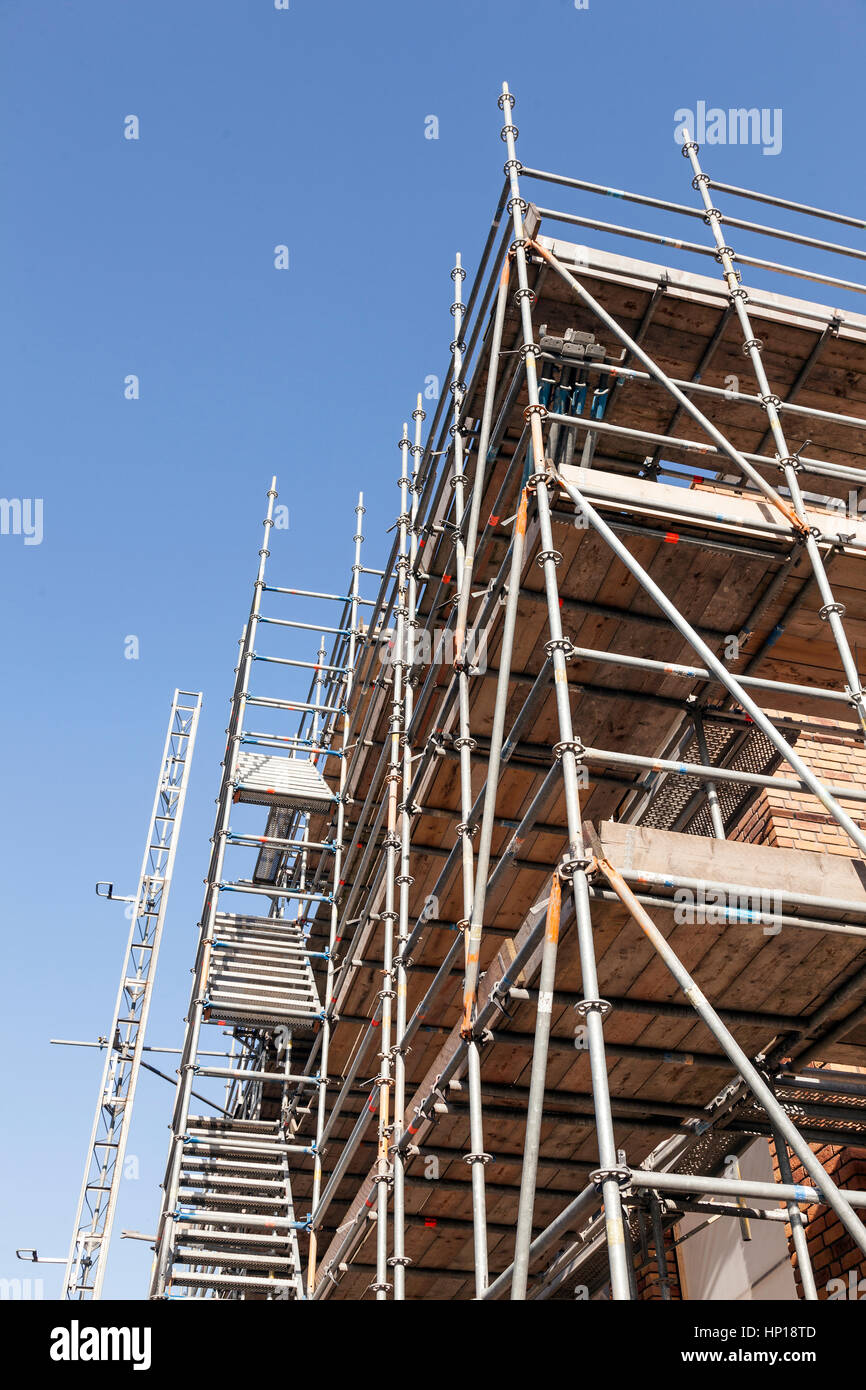 square picture of scaffolding under blue sky on new housing facility in ...