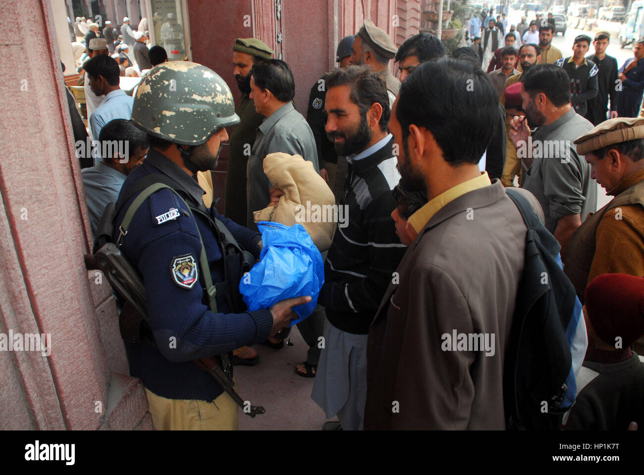 Peshawar, Pakistan. 17th Feb, 2017. A policeman checks belongings of a ...