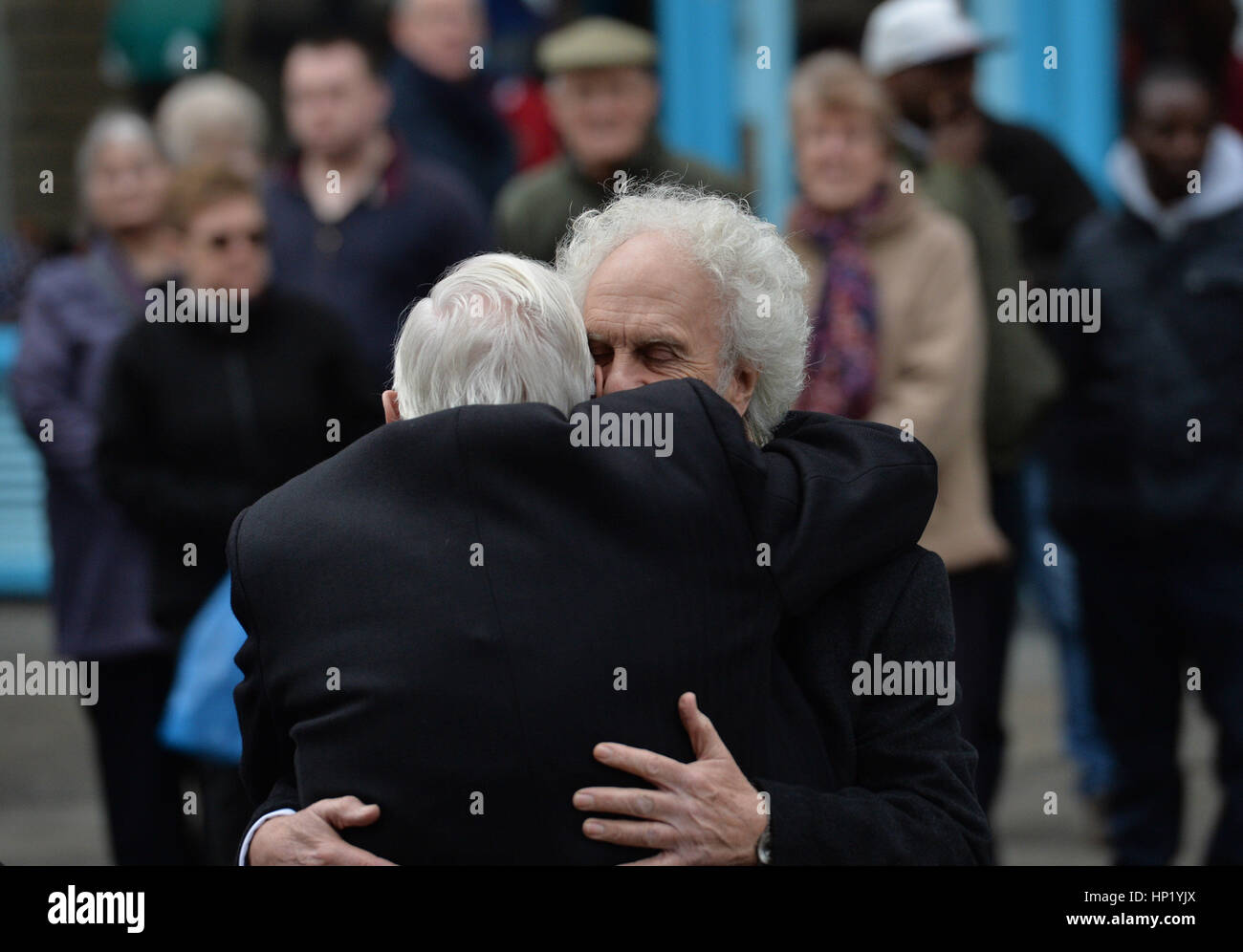 Entertainer and comedian Keith Simmons (facing) hugs a fellow mourner ...